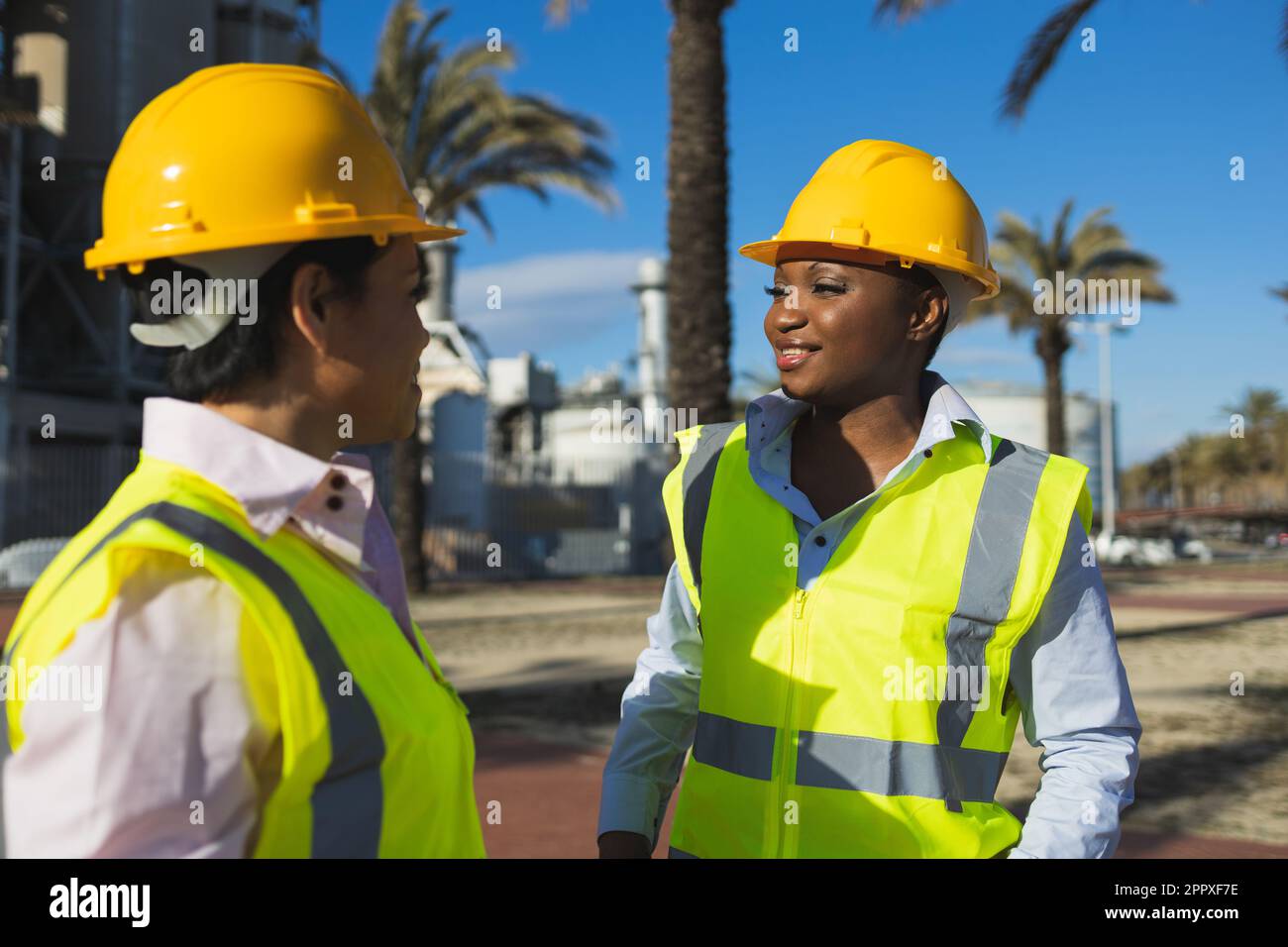 Happy young African American engineers in uniforms and helmets smiling ...