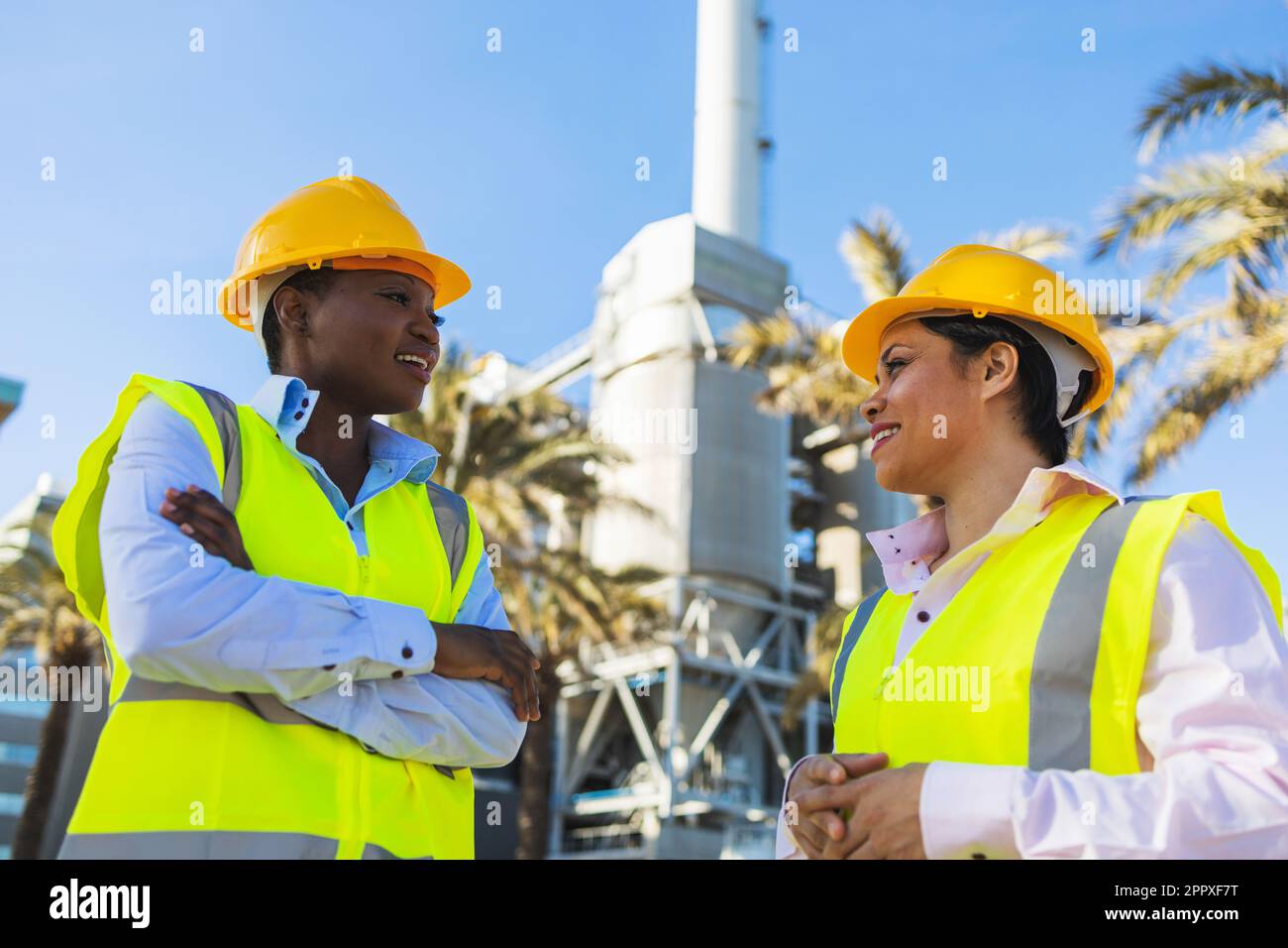 Happy young African American engineers in uniforms and helmets smiling ...