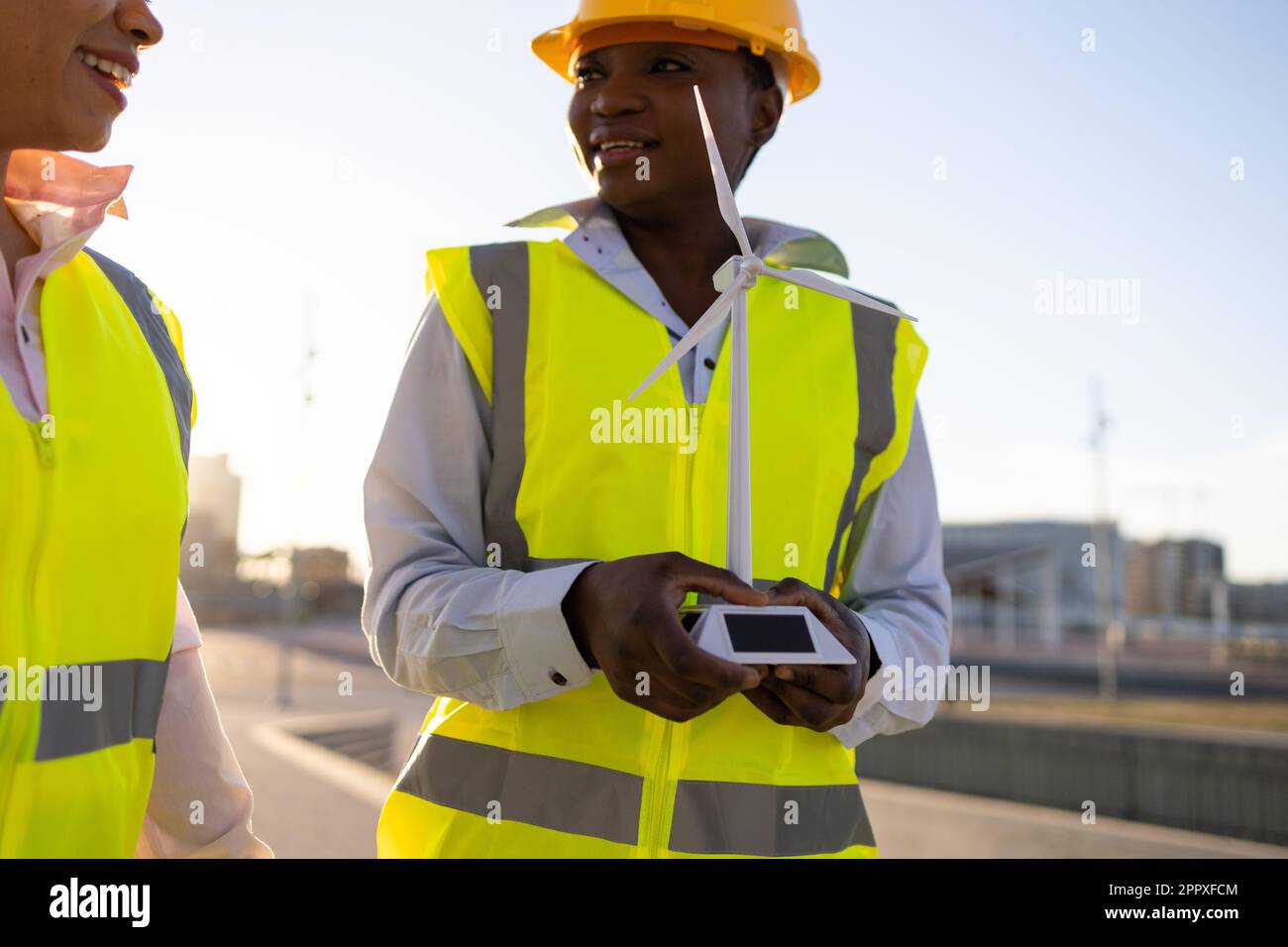 African American female builders in hardhat and uniform using wind ...