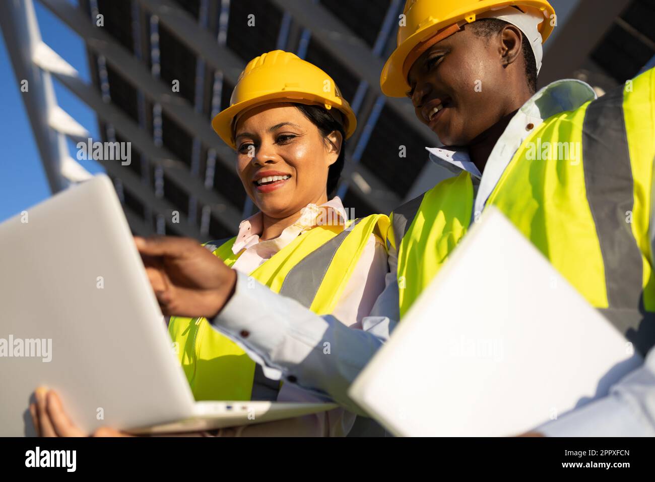 Low angle of young happy African American female builders in hardhat ...
