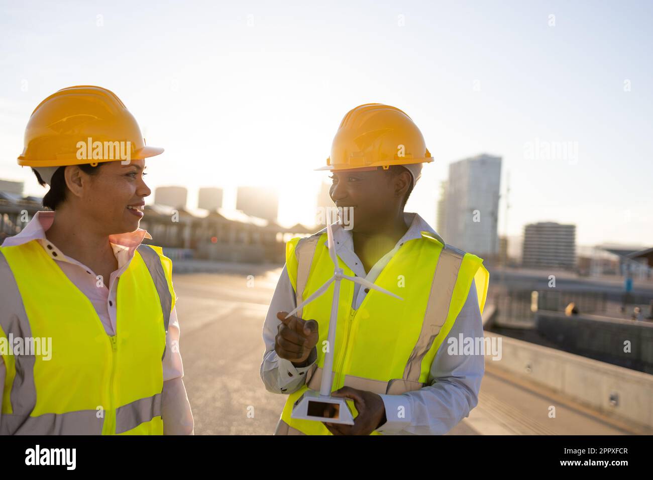 African American female builders in hardhat and uniform using wind ...