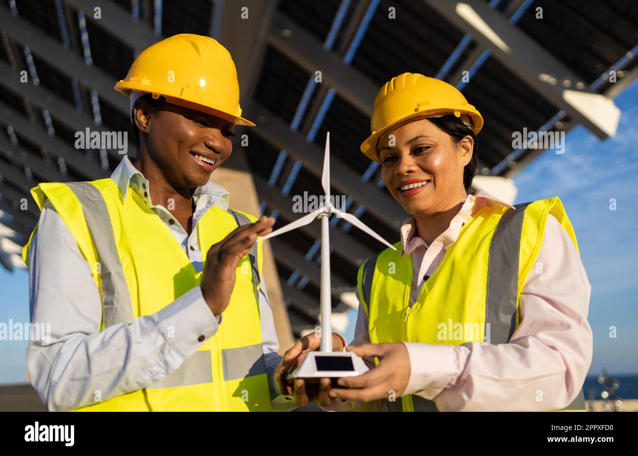 African American female builders in hardhat and uniform using wind ...