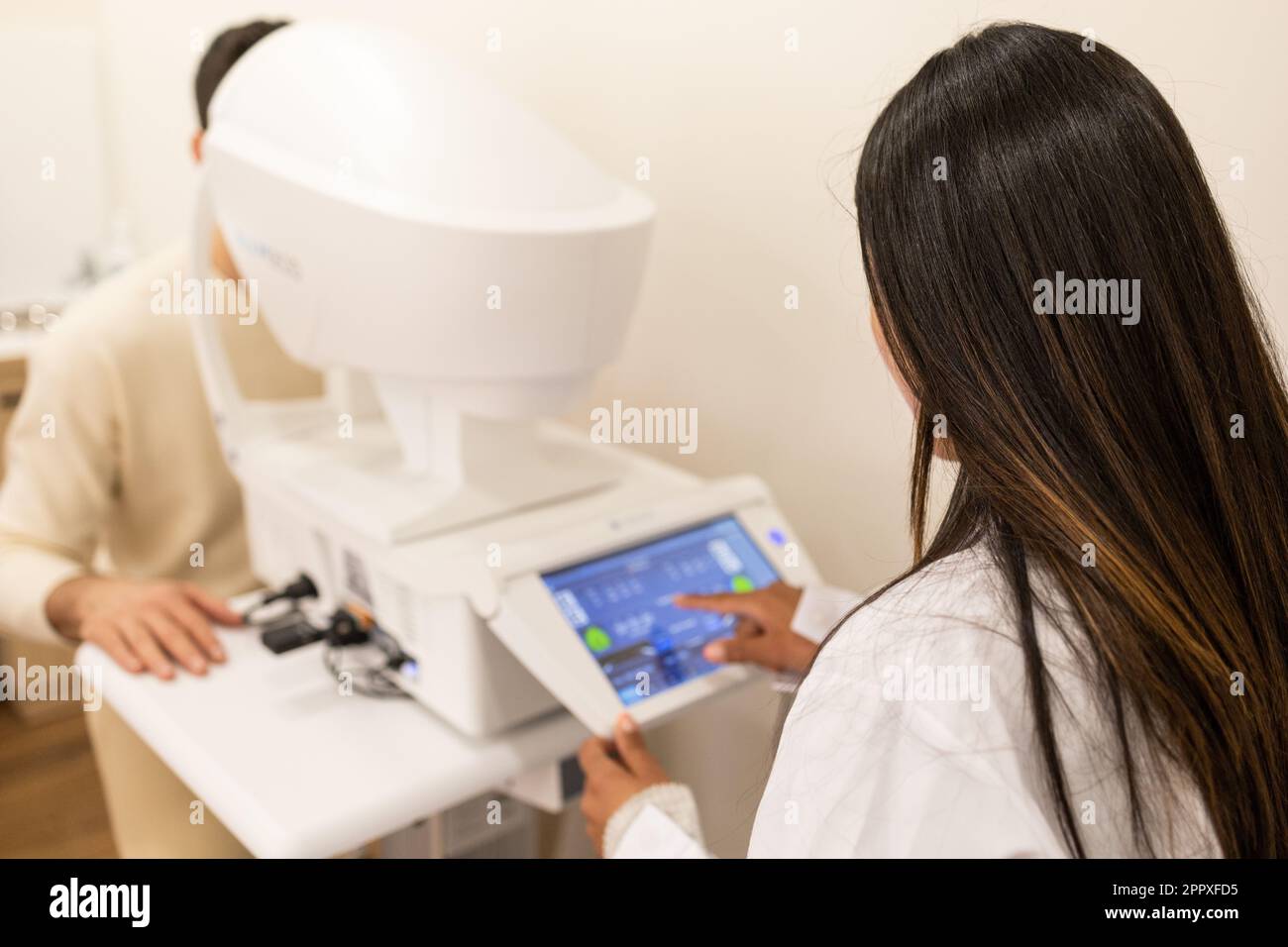 Back view of unrecognizable eye doctor examining young man eyes while ...
