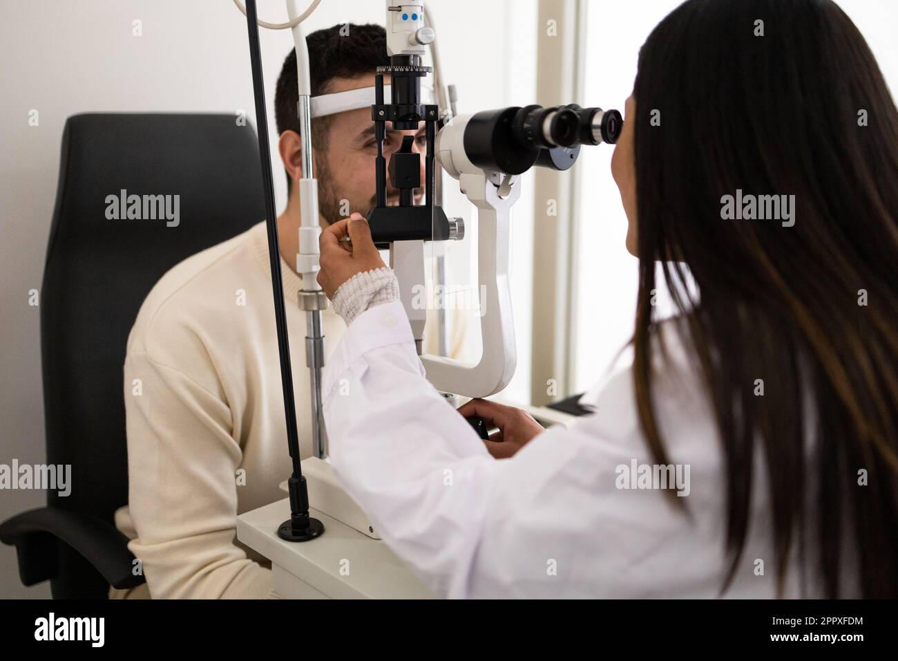 Side view of positive bearded male patient looking at slit lamp while ...