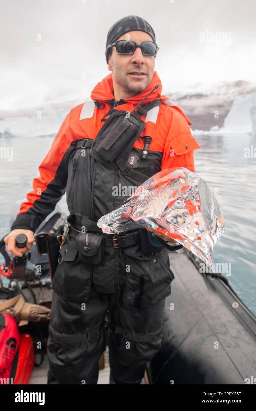 Expedition leader holding crystal clear ice from an iceberg, Rode Fjord ...