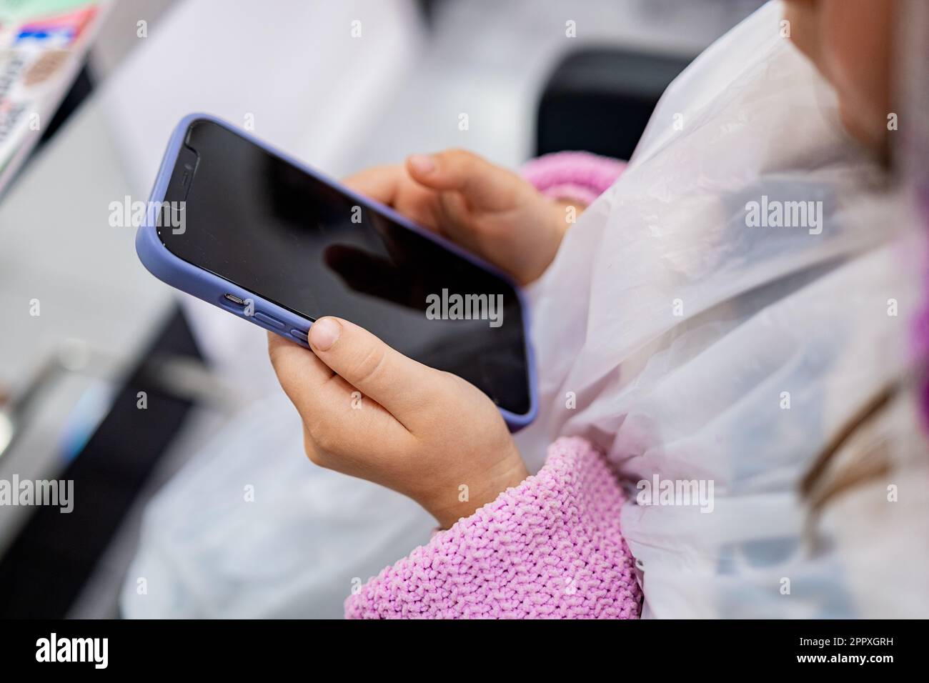 Crop child looking at screen of mobile phone in hands with reflection ...