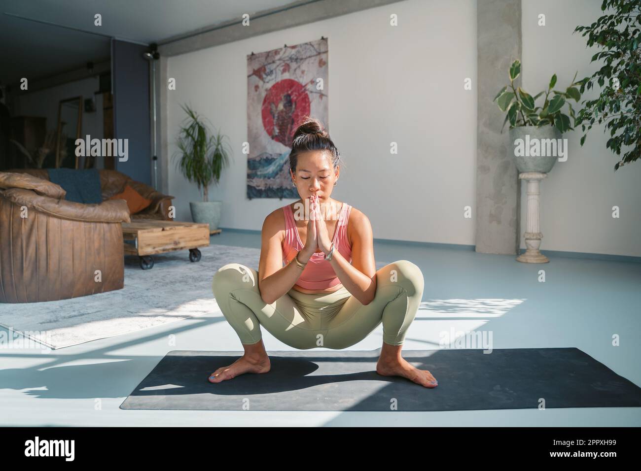Full body of calm young Asian female in activewear performing Malasana ...