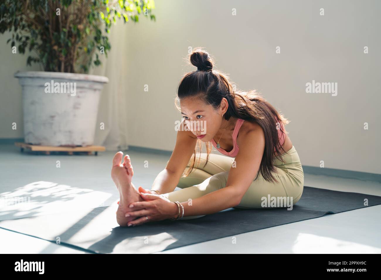 Full body of concentrated young Asian female in sportswear practicing ...