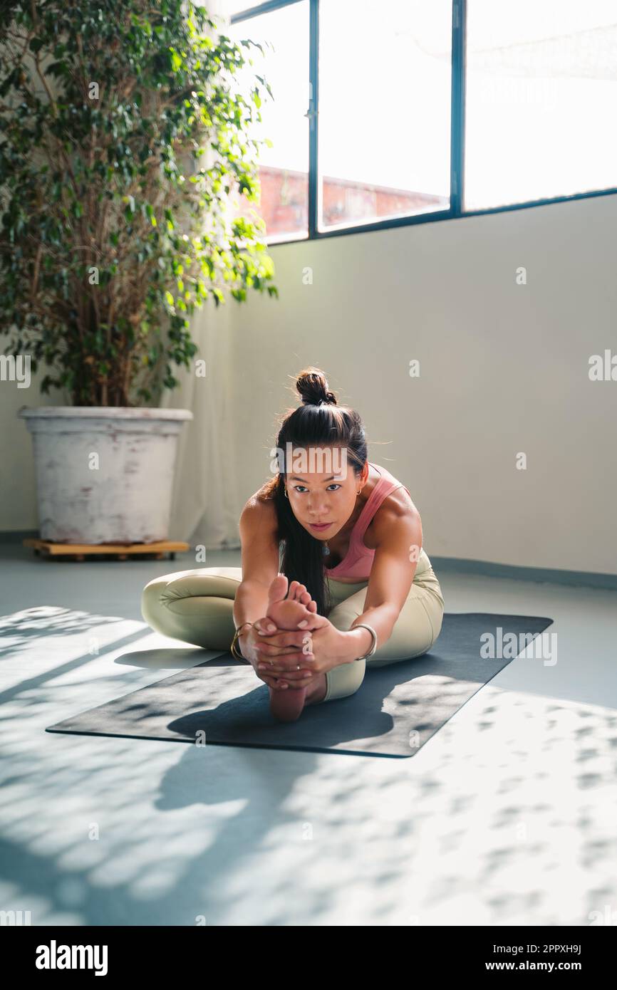 Full body of concentrated young Asian female in sportswear practicing ...