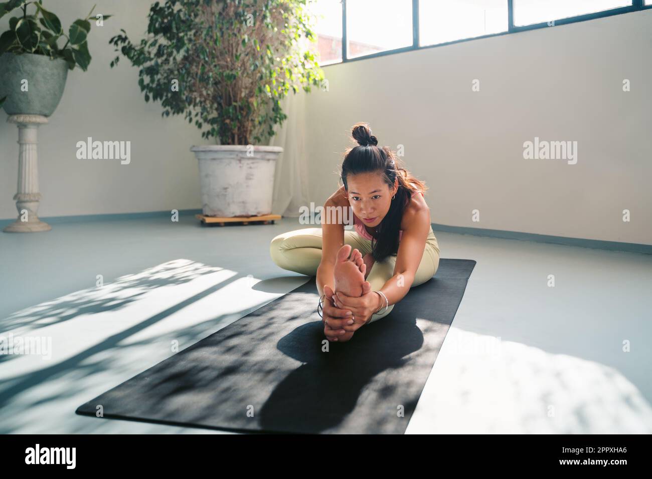 Full body of concentrated young Asian female in sportswear practicing ...