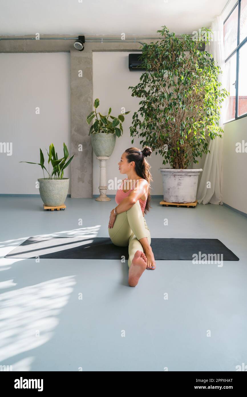 Full body of calm young female in sportswear meditating in Marichyasana ...