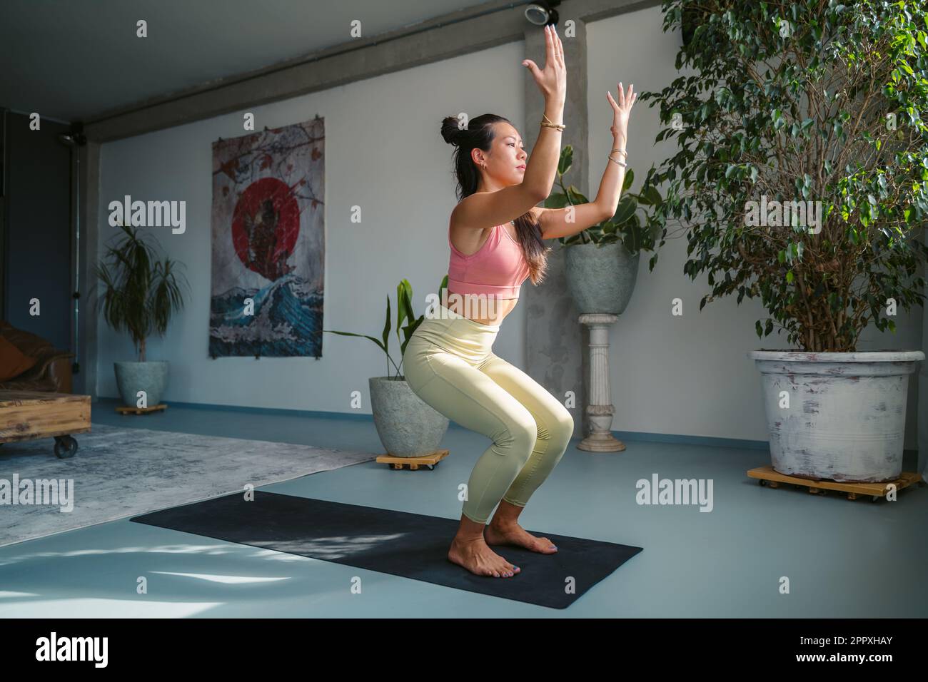 Full body of concentrated young Asian female in activewear performing ...