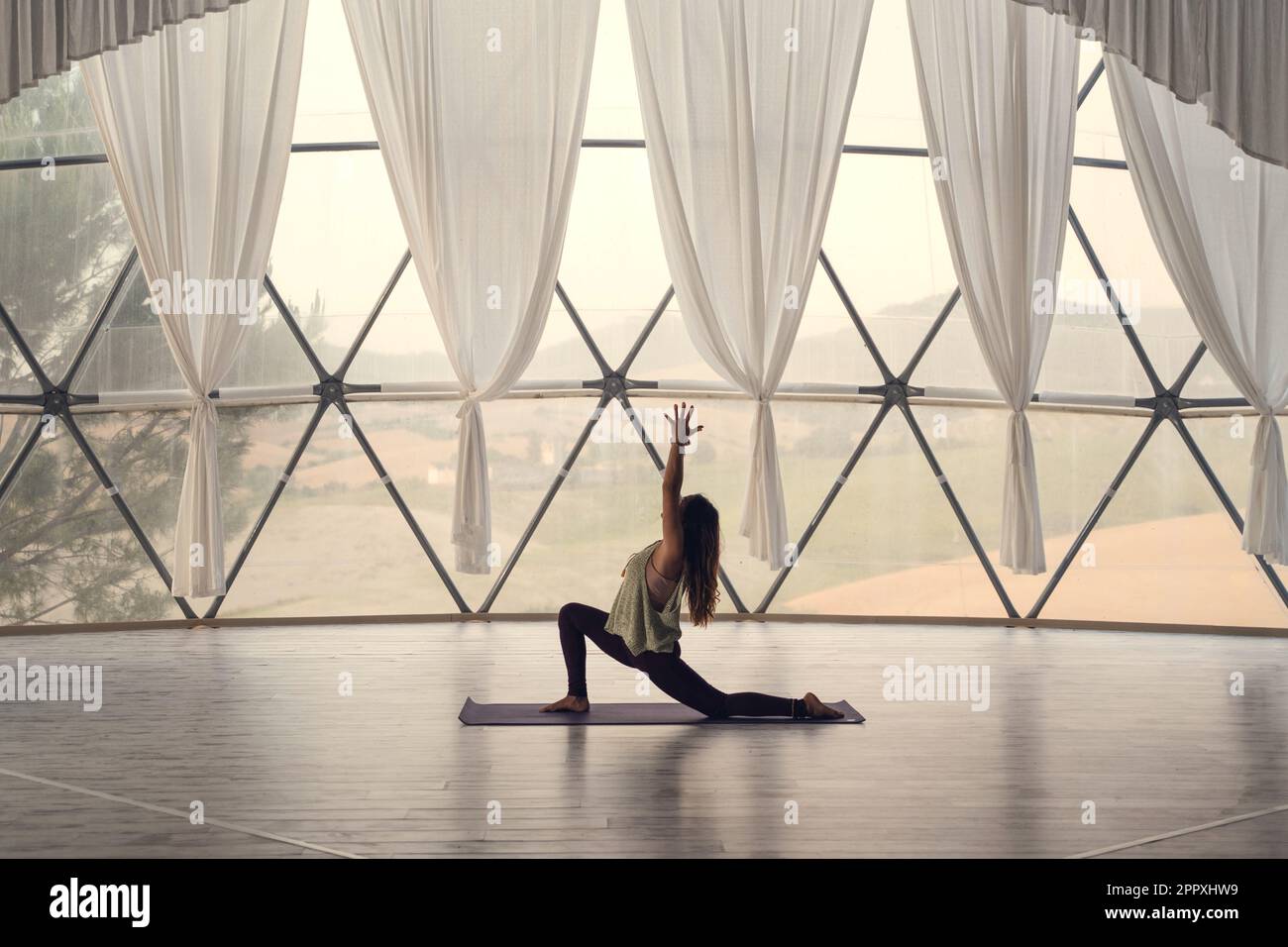 Side view of female dancer in black leggings performing dance pose ...