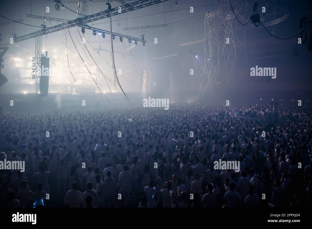Crowd of people standing on dance floor near illuminated stage during ...