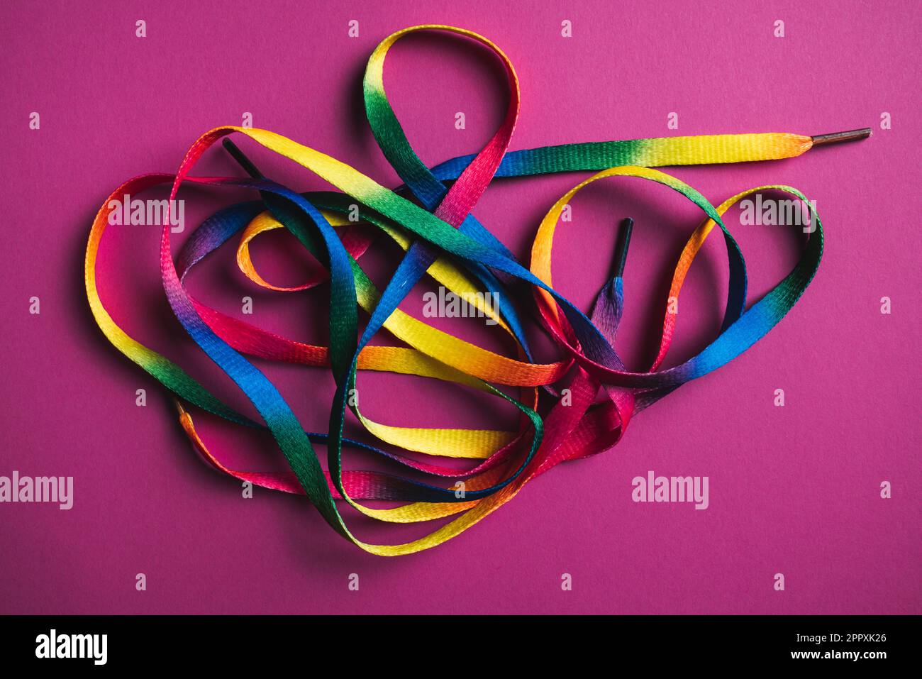 From above of arrange rainbow colored shoelaces in mess on pink ...