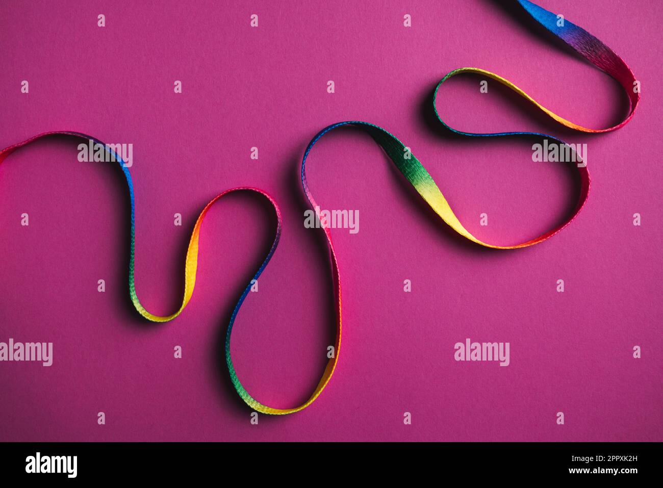From above of arrange rainbow colored shoelaces in mess on pink ...