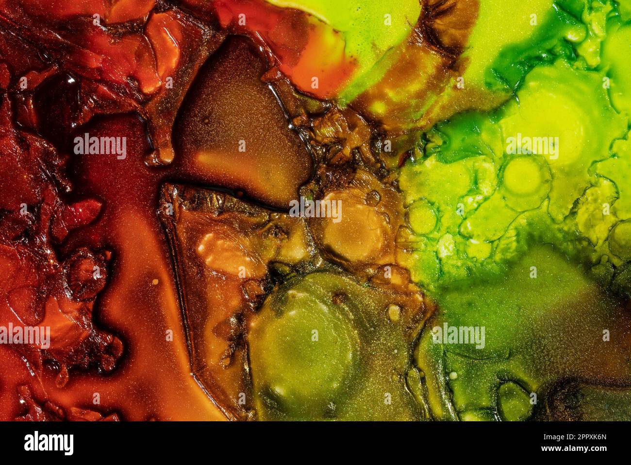 Spills of multicolored metallic dye mixing and spreading on black ...