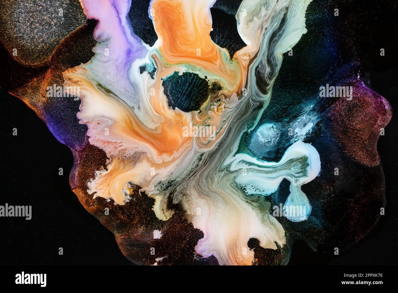 Spills of multicolored metallic dye mixing and spreading on black ...