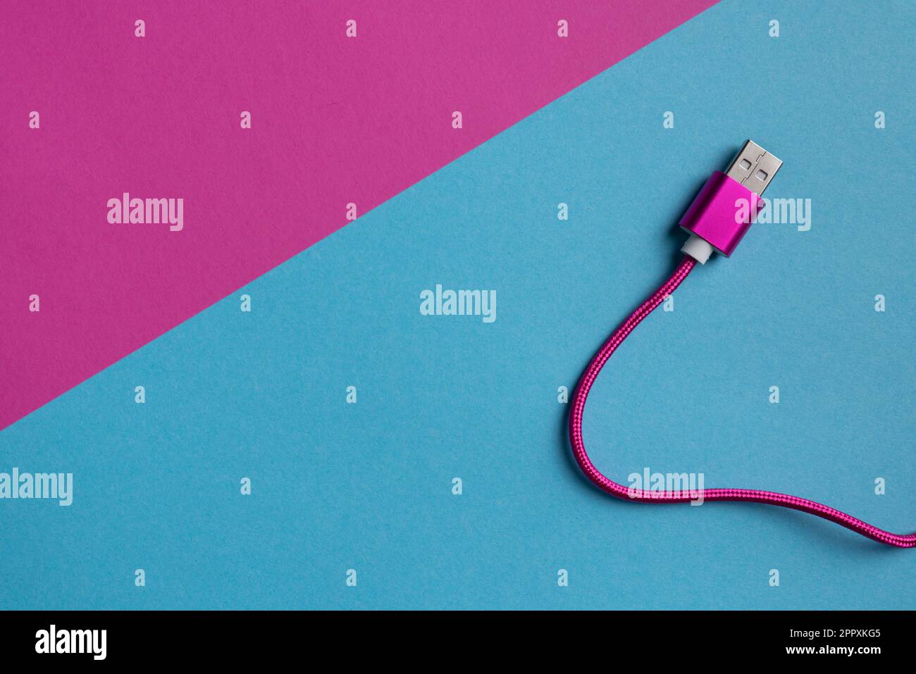 Top view of neon pink colored USB cable on colorful cardboard ...