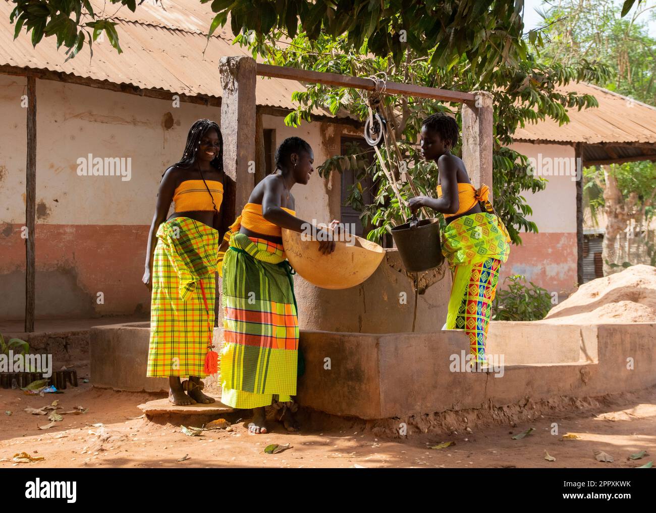 Group of African females in traditional colorful clothes drawing water ...