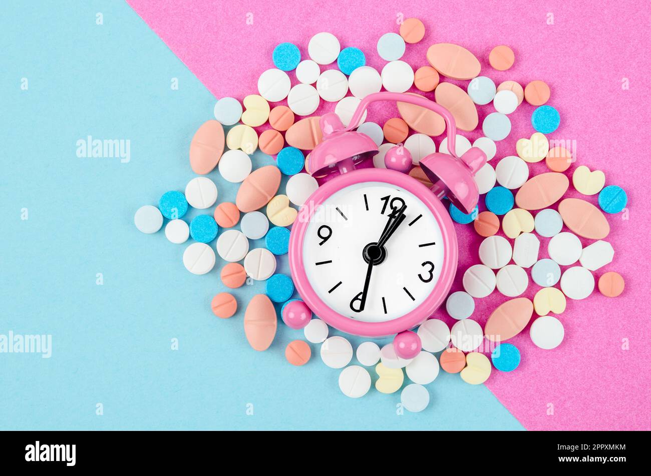 Alarm clock and many drug on a pink colour background. Taking medicine ...