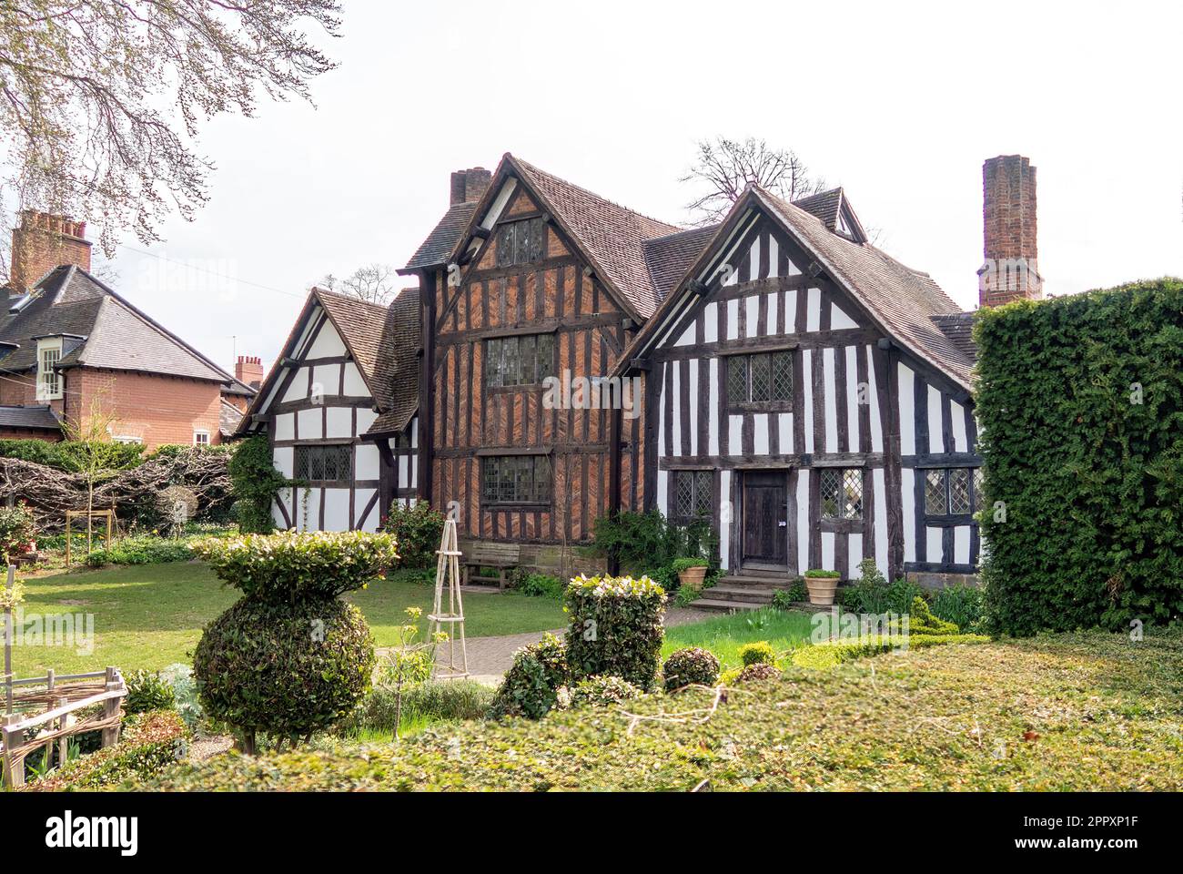 A vintage timber-framed building with a green garden. Selly Manor ...