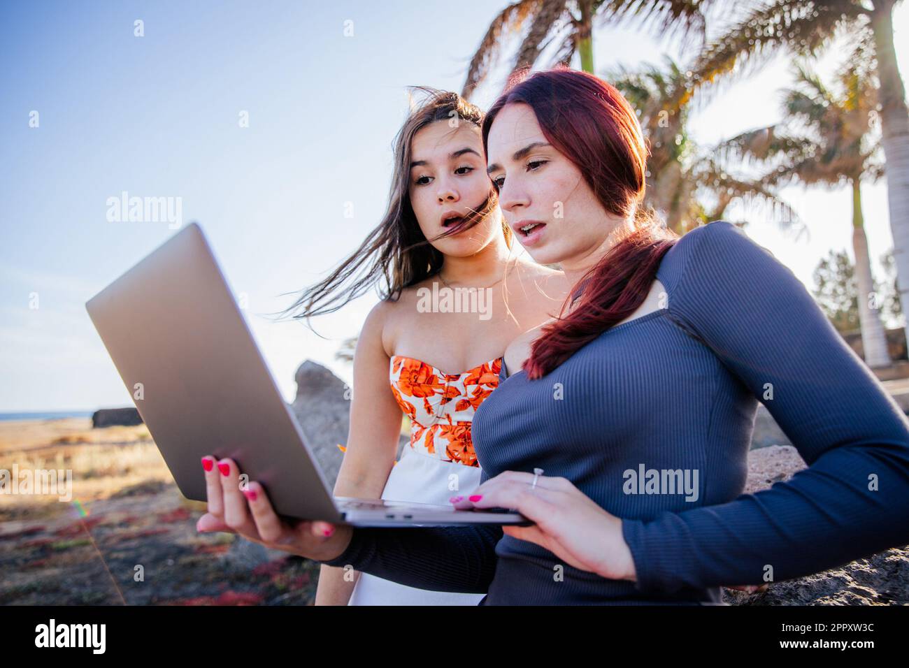 Two girls are using the laptop and have surprised expressions while ...
