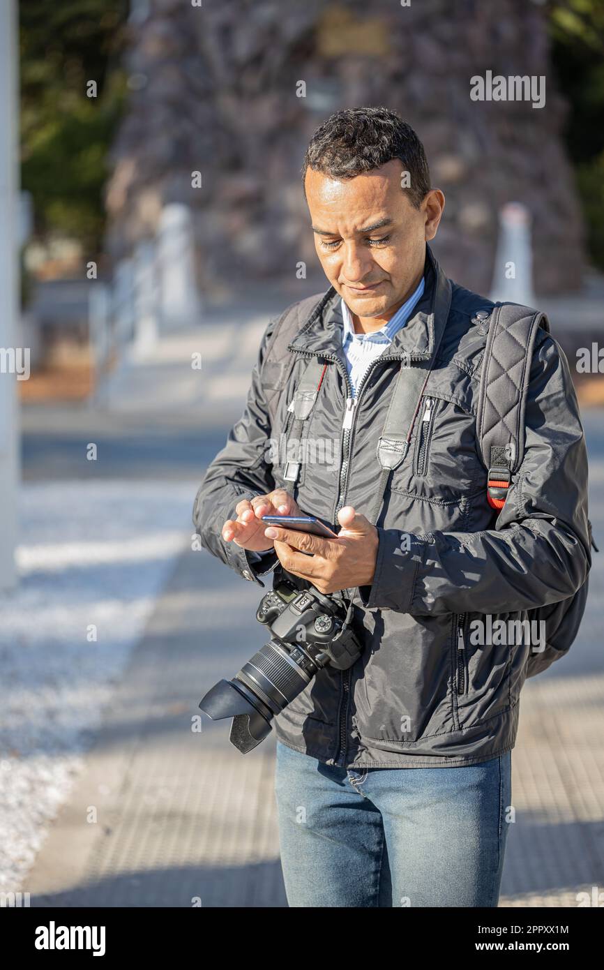 Photographer working on the street and sending text messages with his ...