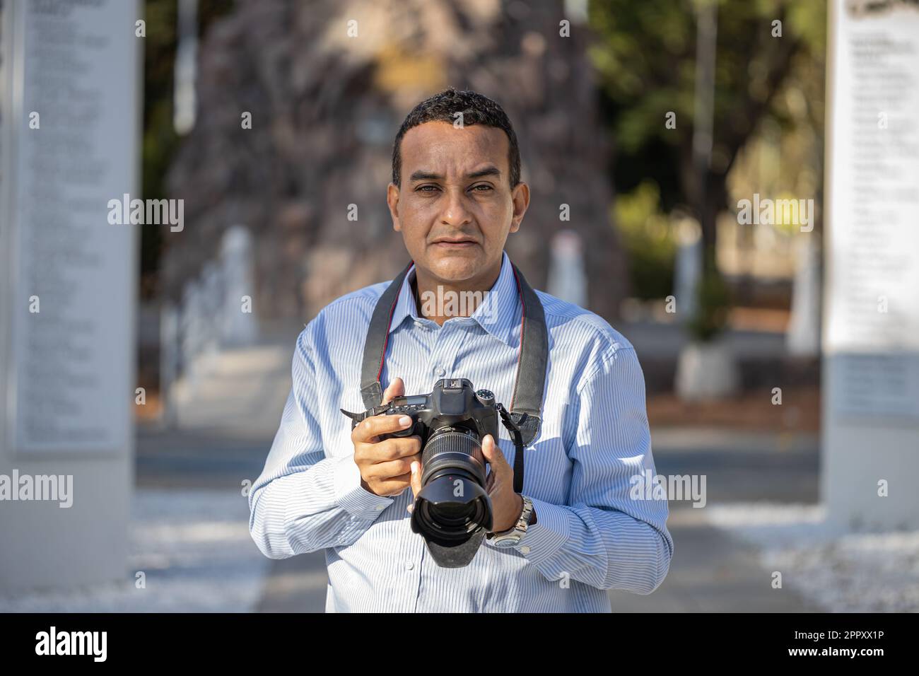 Close-up of photographer looking straight ahead with his camera in hand ...