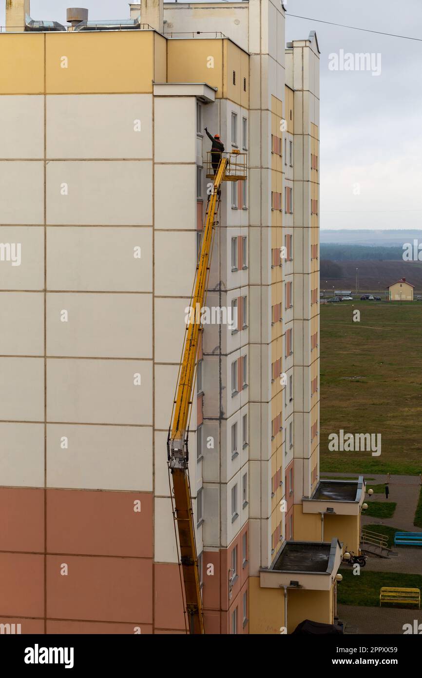 Worker in the basket of a car lift are repairing the facade of ...