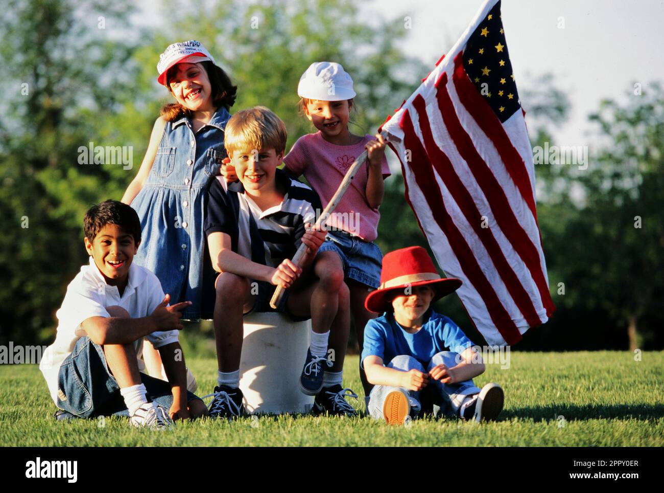 Portrait of a mixed racial group of children holding an American flag ...