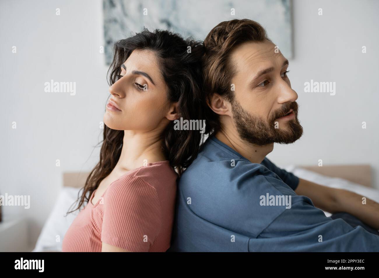 Sad couple sitting back to back in blurred bedroom at home,stock image ...