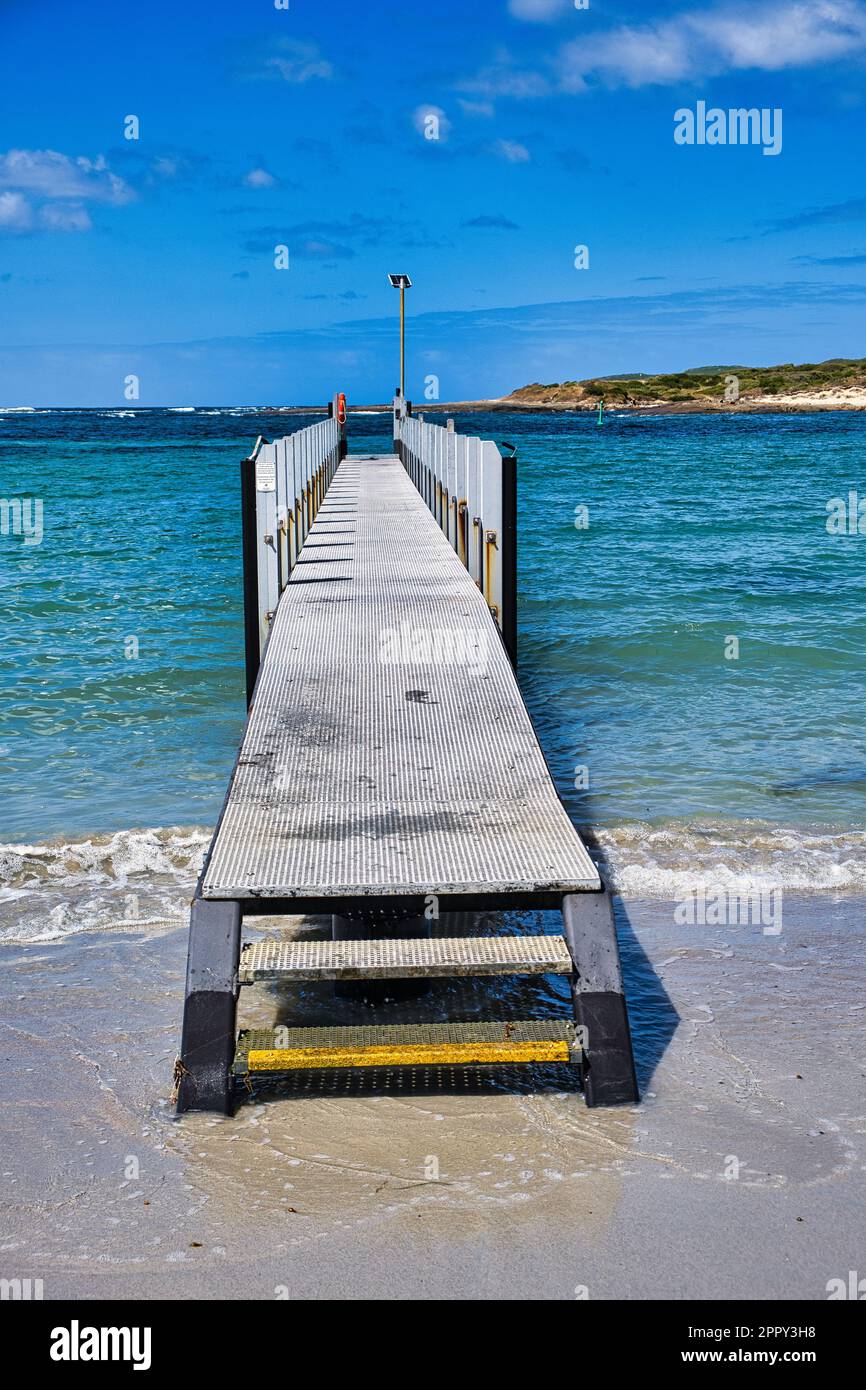 Long jetty in a turquoise sea, coast with dunes in the background ...