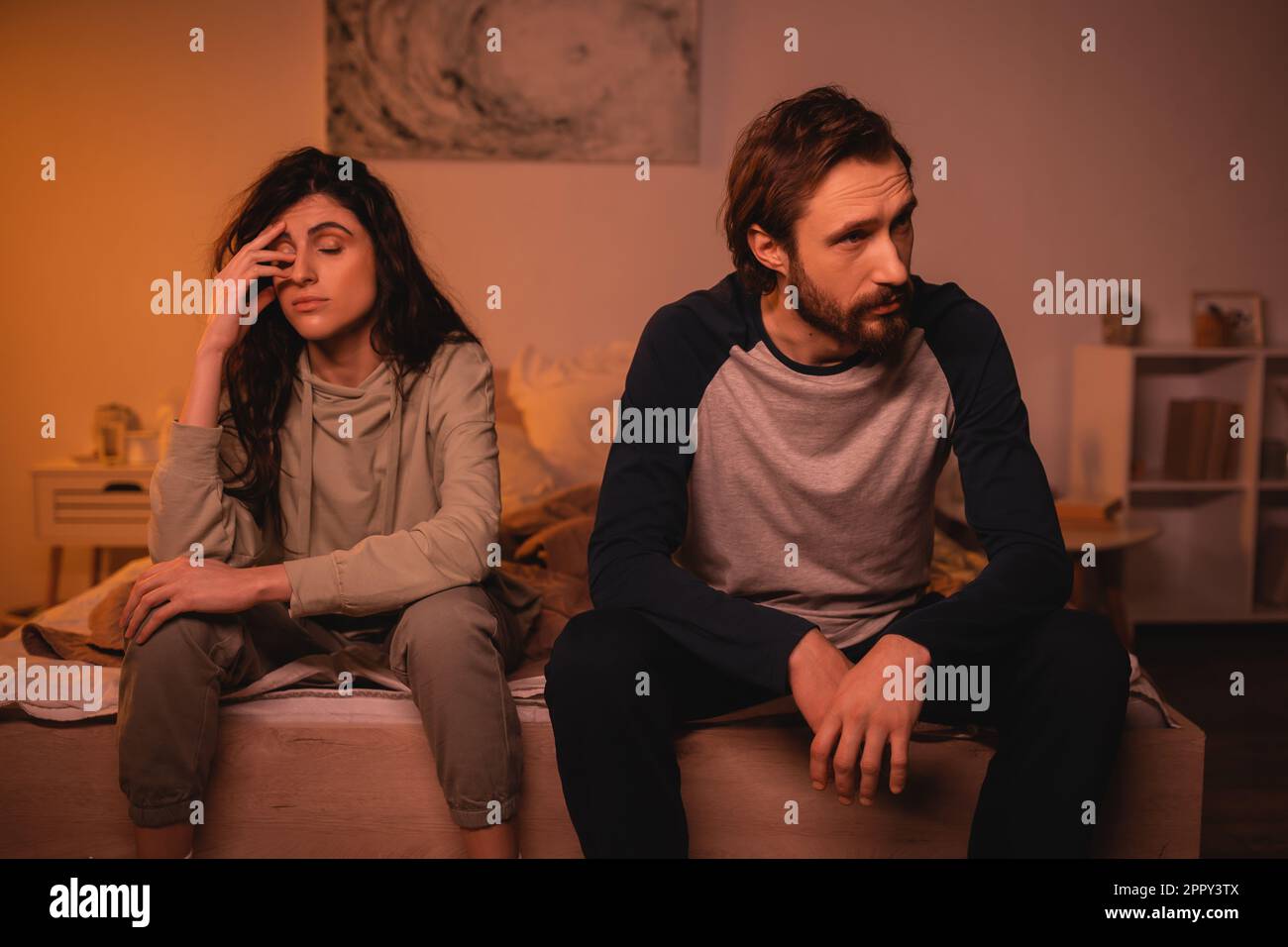 Sad couple with relationship difficulties sitting on bed in evening,stock image Stock Photo - Alamy