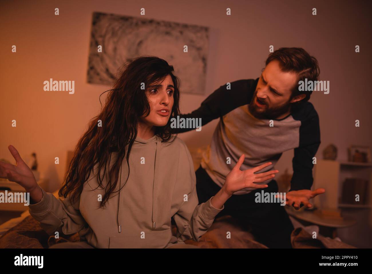 Aggressive man quarrelling at girlfriend on bed at night,stock image ...