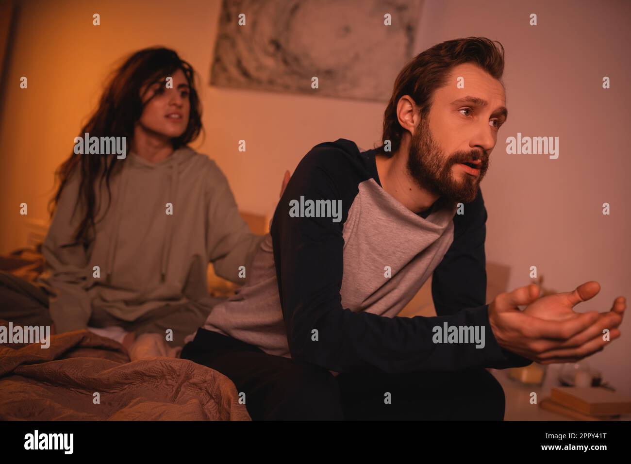 Stressed man sitting near blurred girlfriend quarrelling in bedroom at ...