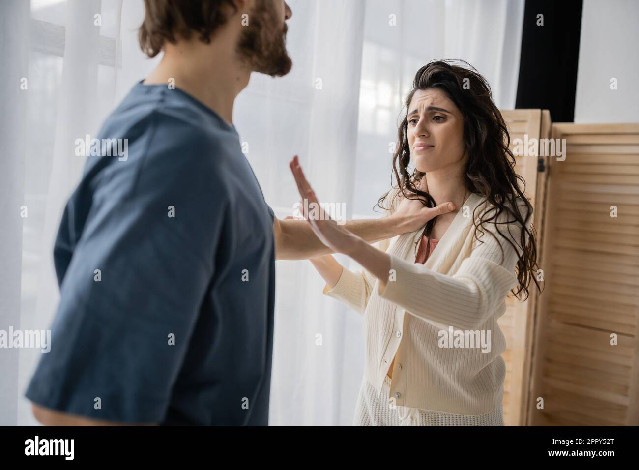 Scared woman showing stop gesture near abusive boyfriend at home,stock ...