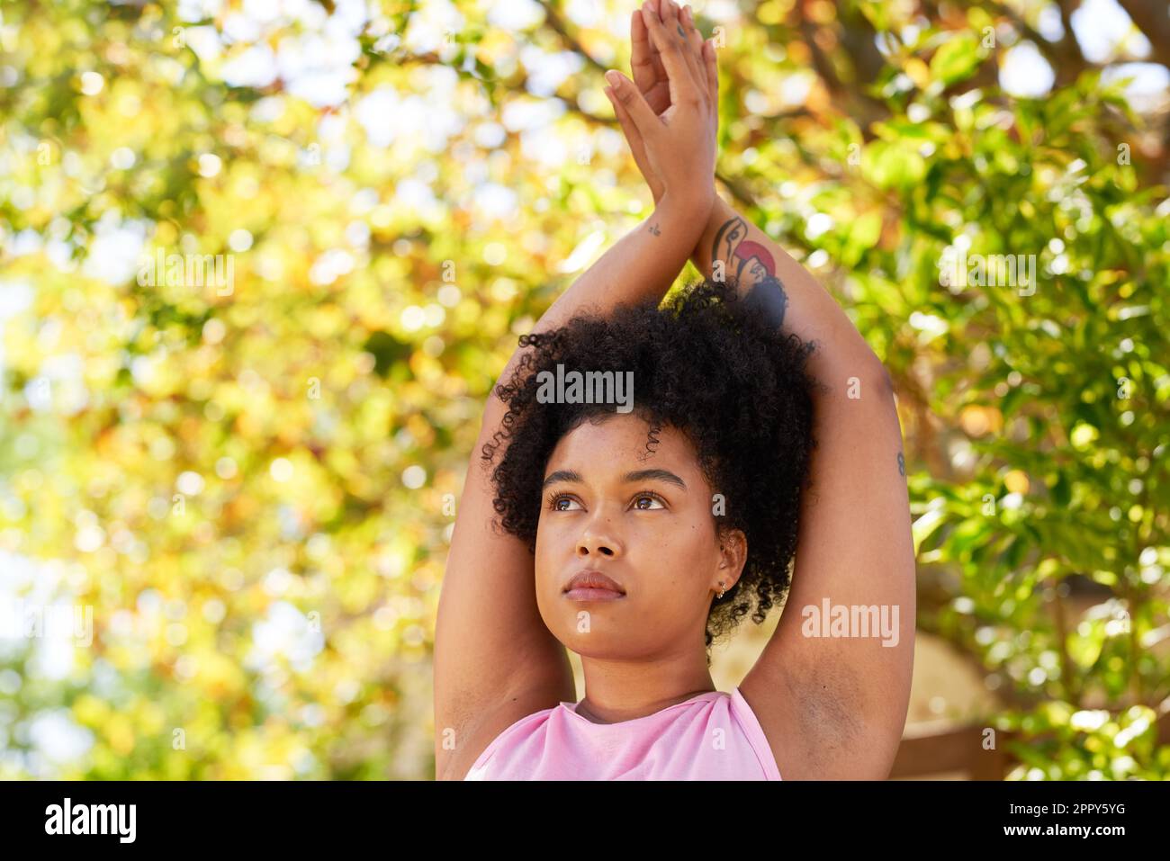 Portrait of young multi-ethnic woman pressing hands in prayer above ...