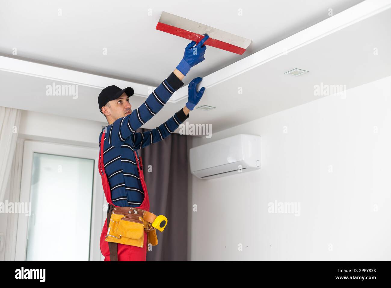 man plasterer construction worker at work, takes plaster from bucket ...