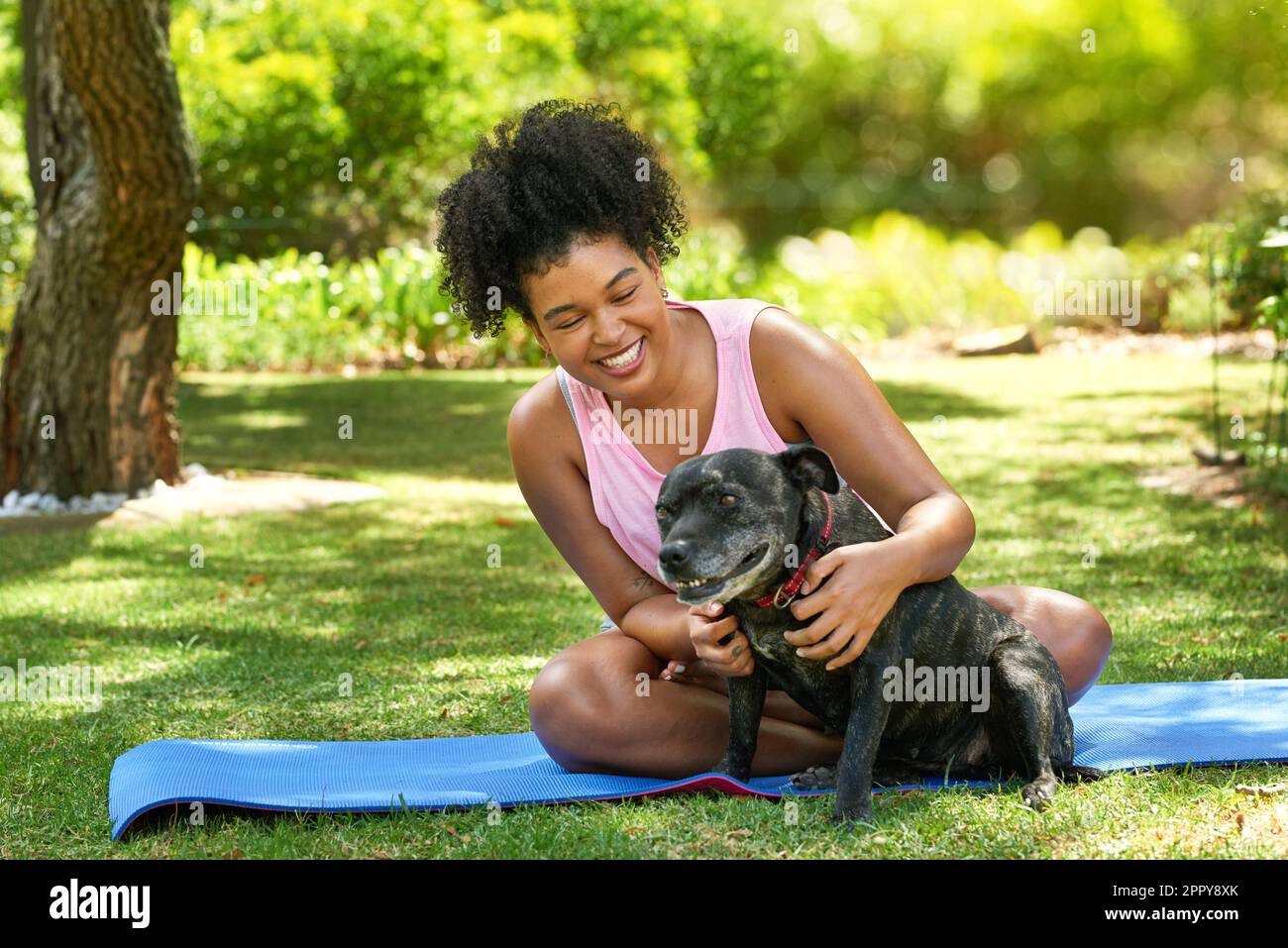 A multi-ethnic woman and her happy dog, giving attention in the park ...