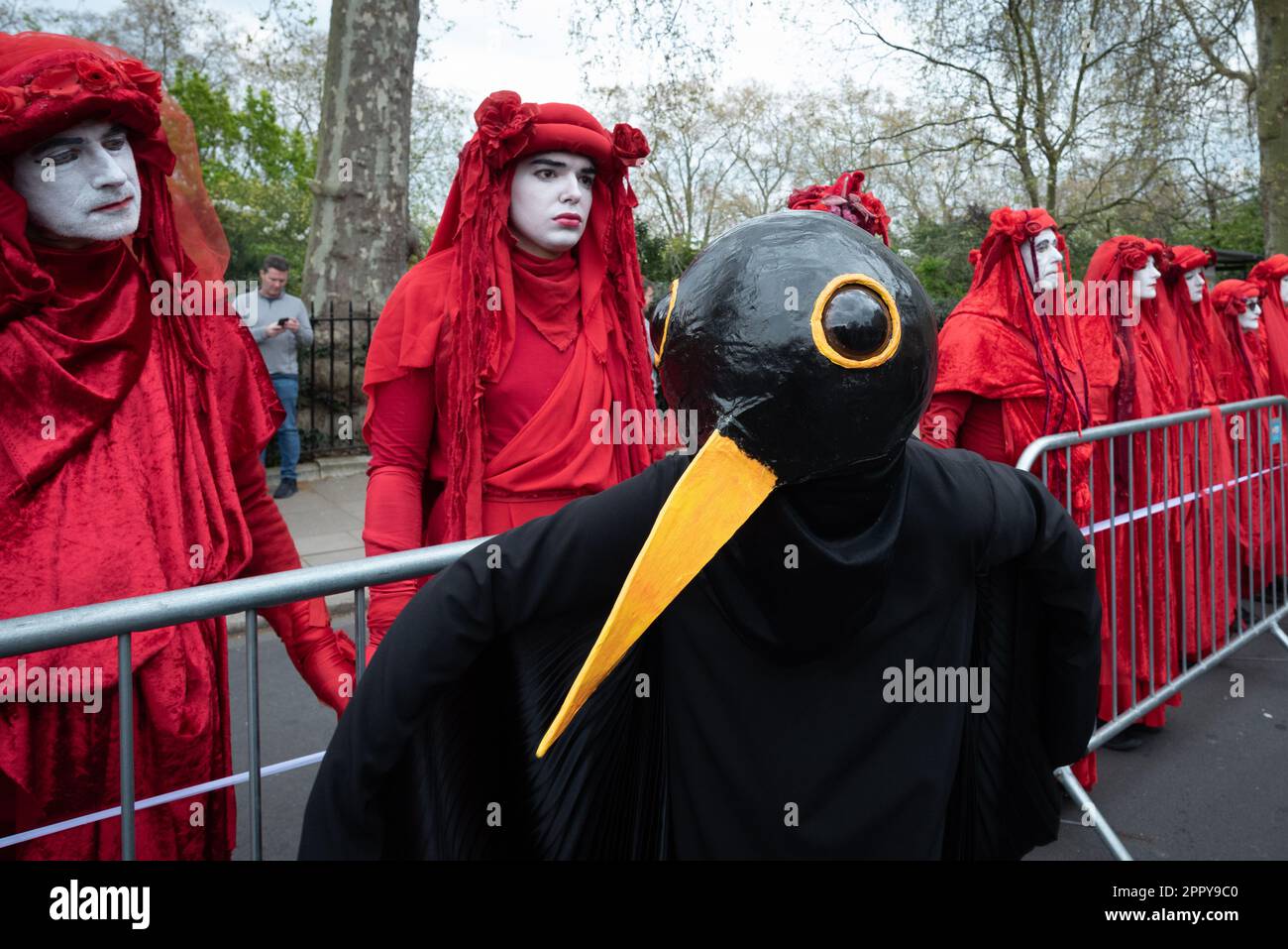 An activist in a bird costume passes the Red Rebel Brigade mime troupe ...