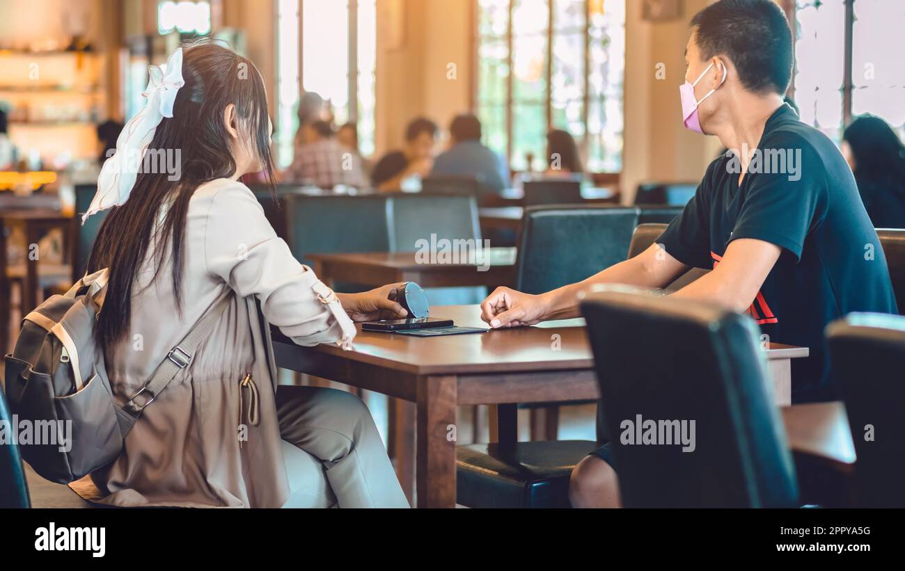 Back view of Asian woman with backpack holding wireless queue caller ...
