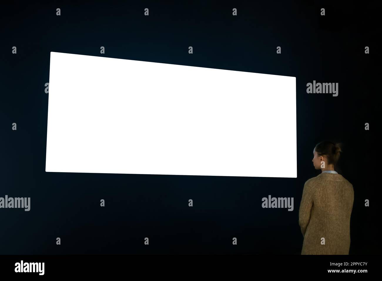 Woman looking at blank wide interactive wall display - white screen ...