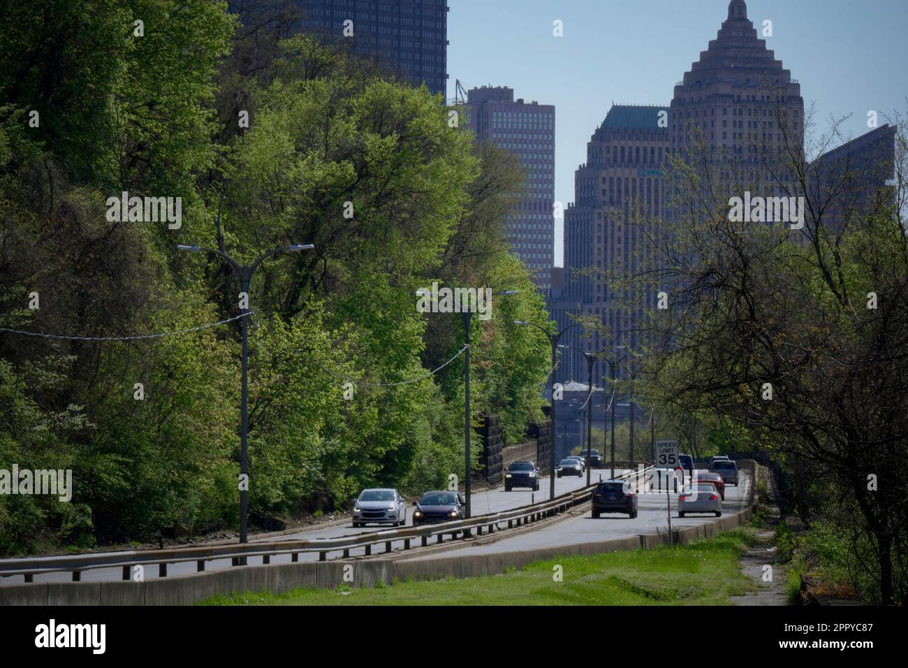The cars driving on a divided highway with city skyscrapers in the ...