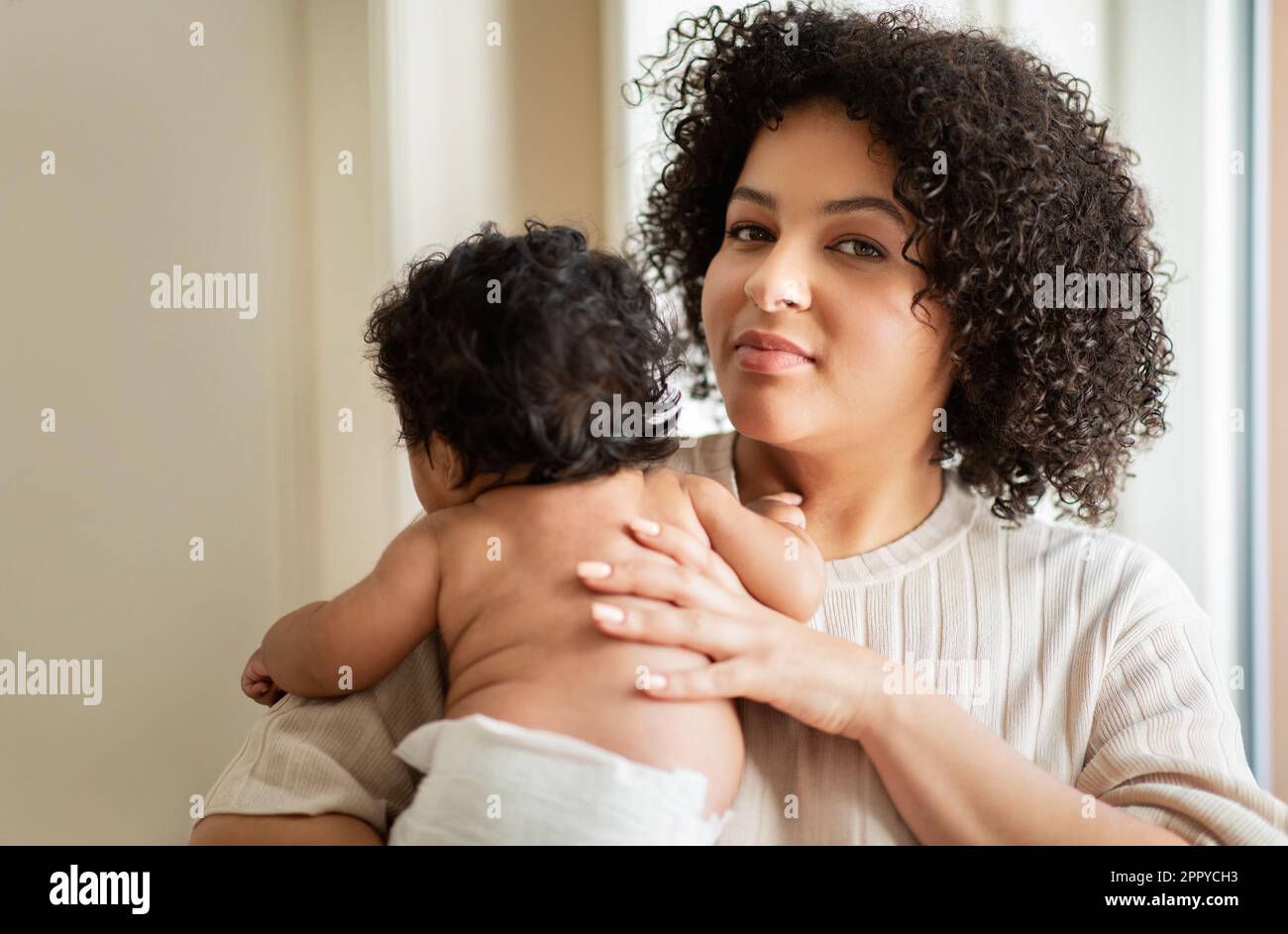 Positive young african american lady hold small baby in diaper in light ...