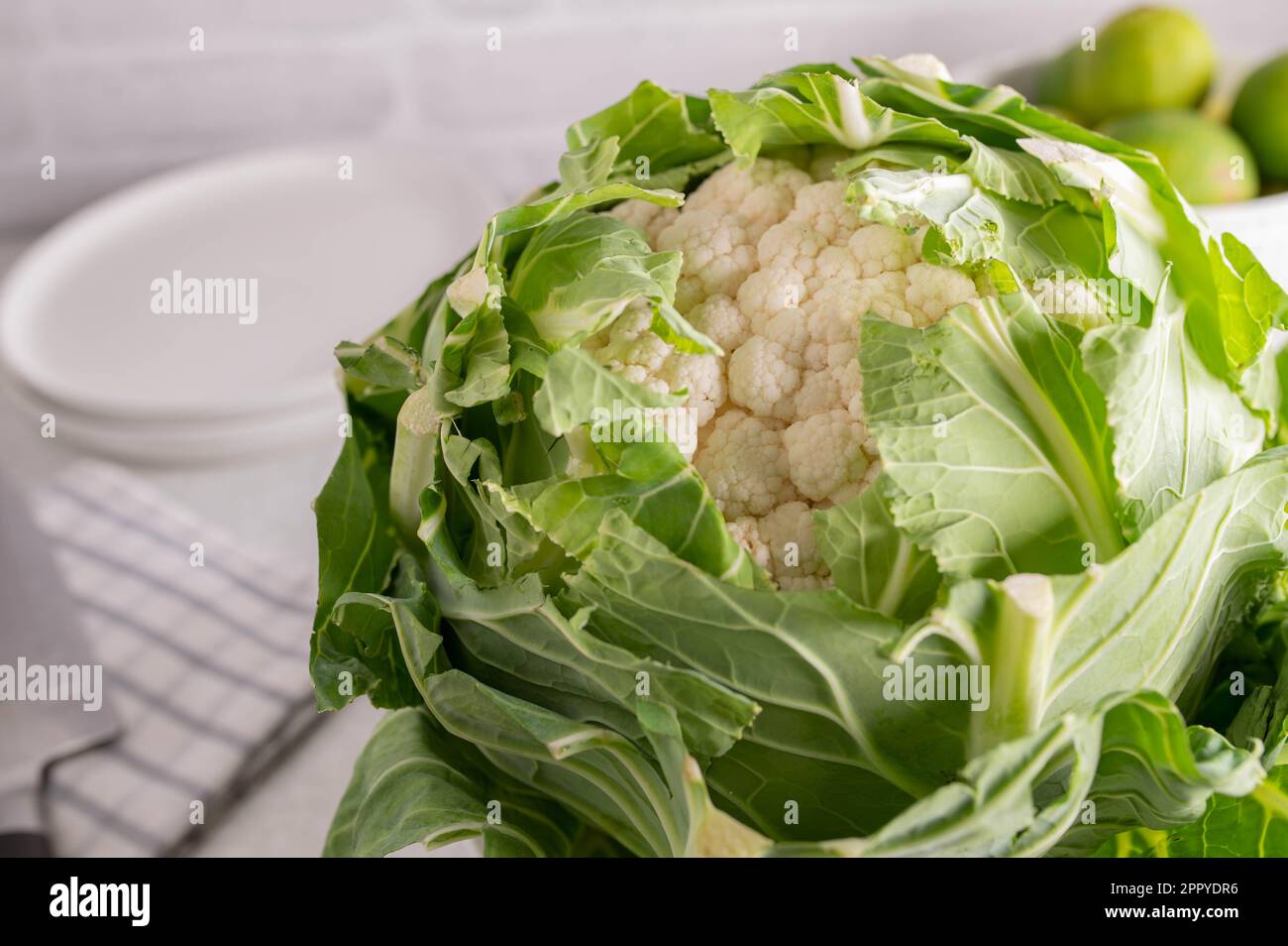 Cauliflower with green leaves on white kitchen counter Stock Photo - Alamy