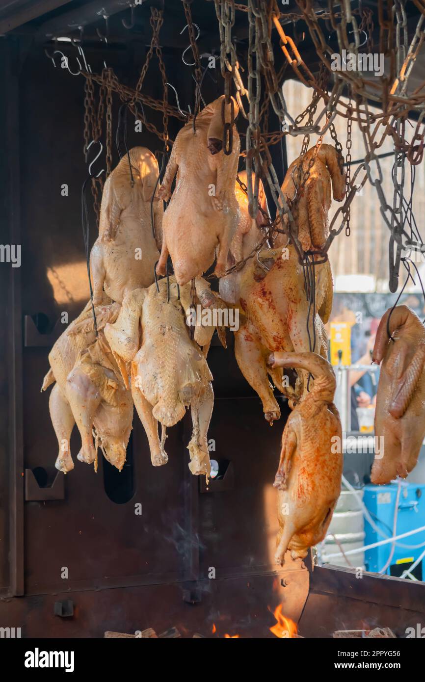 Hanging whole chickens smoking over coals at summer food market Stock ...