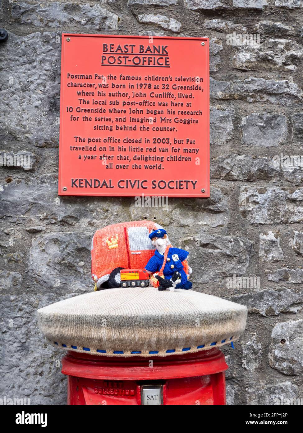 A plaque about postman pat and a postman pat knitted postbox top in ...