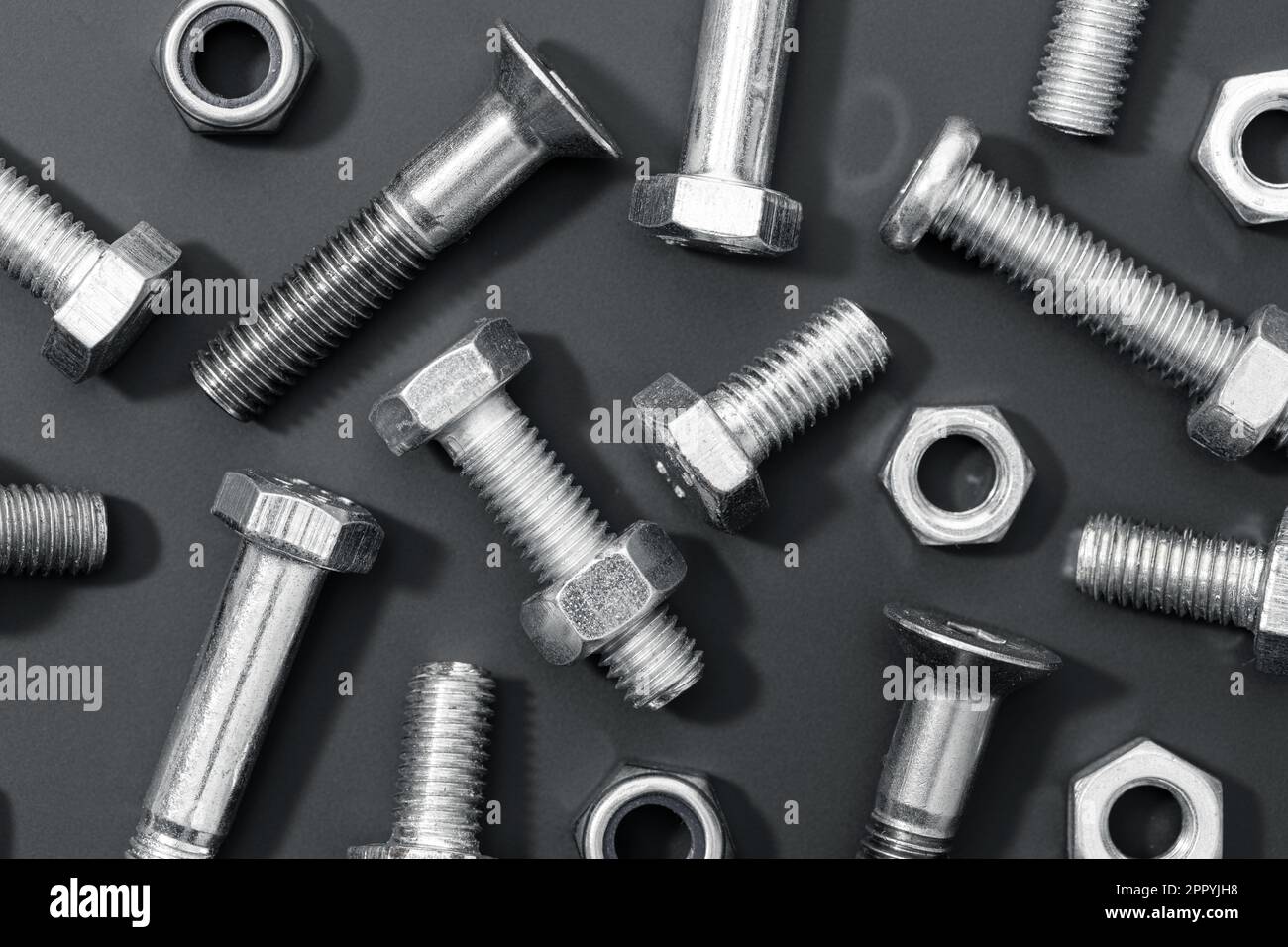 Creative background of a variety of metallic nuts and bolts on black ...
