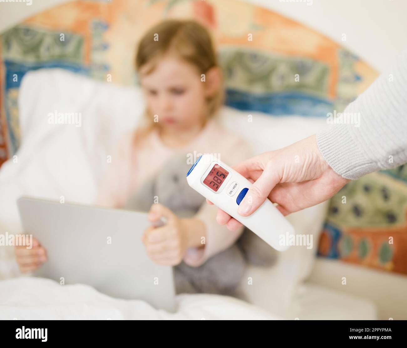 Kid sitting in bed with tablet and furry toy and woman hand holding ...